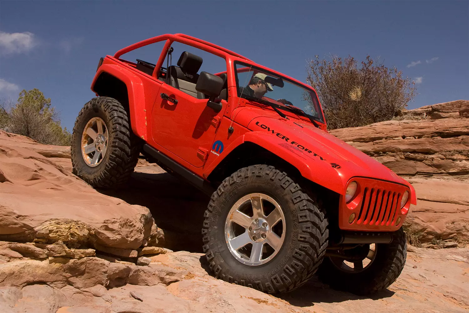 Un Jeep Wrangler rouge avec d'énormes pneus rampant à l'Easter Jeep Safari