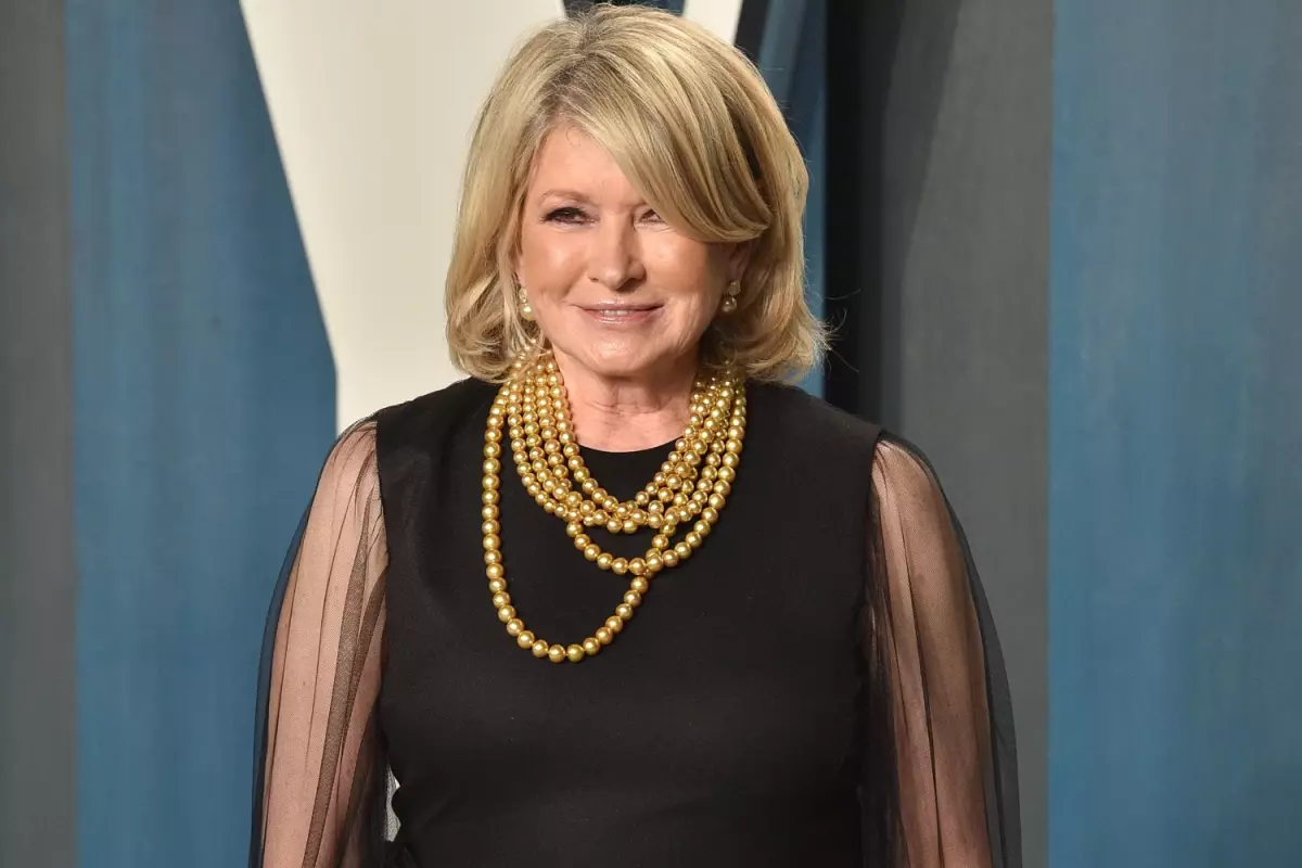 Martha Stewart yn ystumio mewn ffrog ddu a mwclis aur