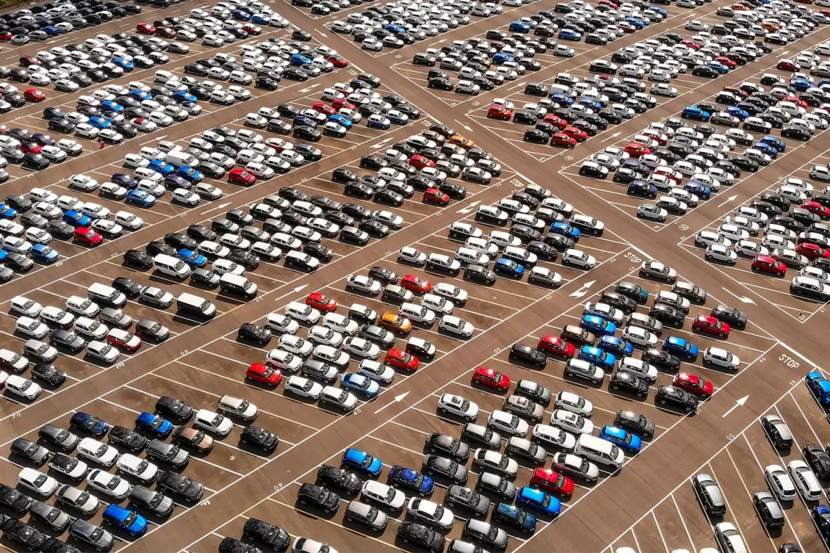 Cientos de autos, camiones y camionetas estacionados en un gran estacionamiento durante el día