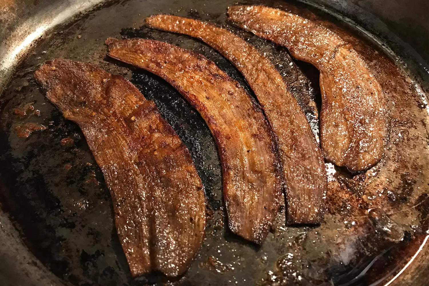 Wajan besi cor Smithey dengan empat potong daging kulit pisang. Ya, buah, daging palsu, daging vegetarian dan vegan rasanya enak, jika Anda mengikuti resep ini.