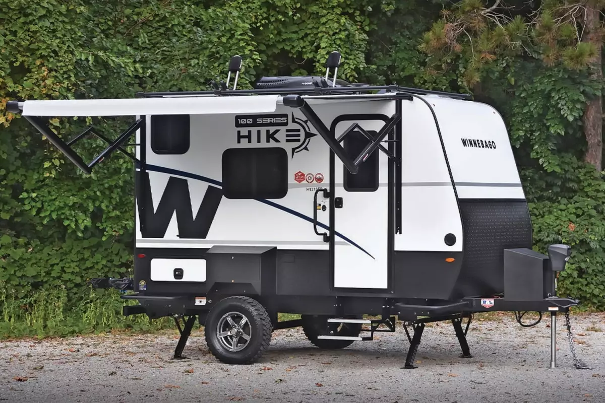 El nuevo remolque de viaje Hike 100 de Winnebago sentado en un terreno de grava en el bosque