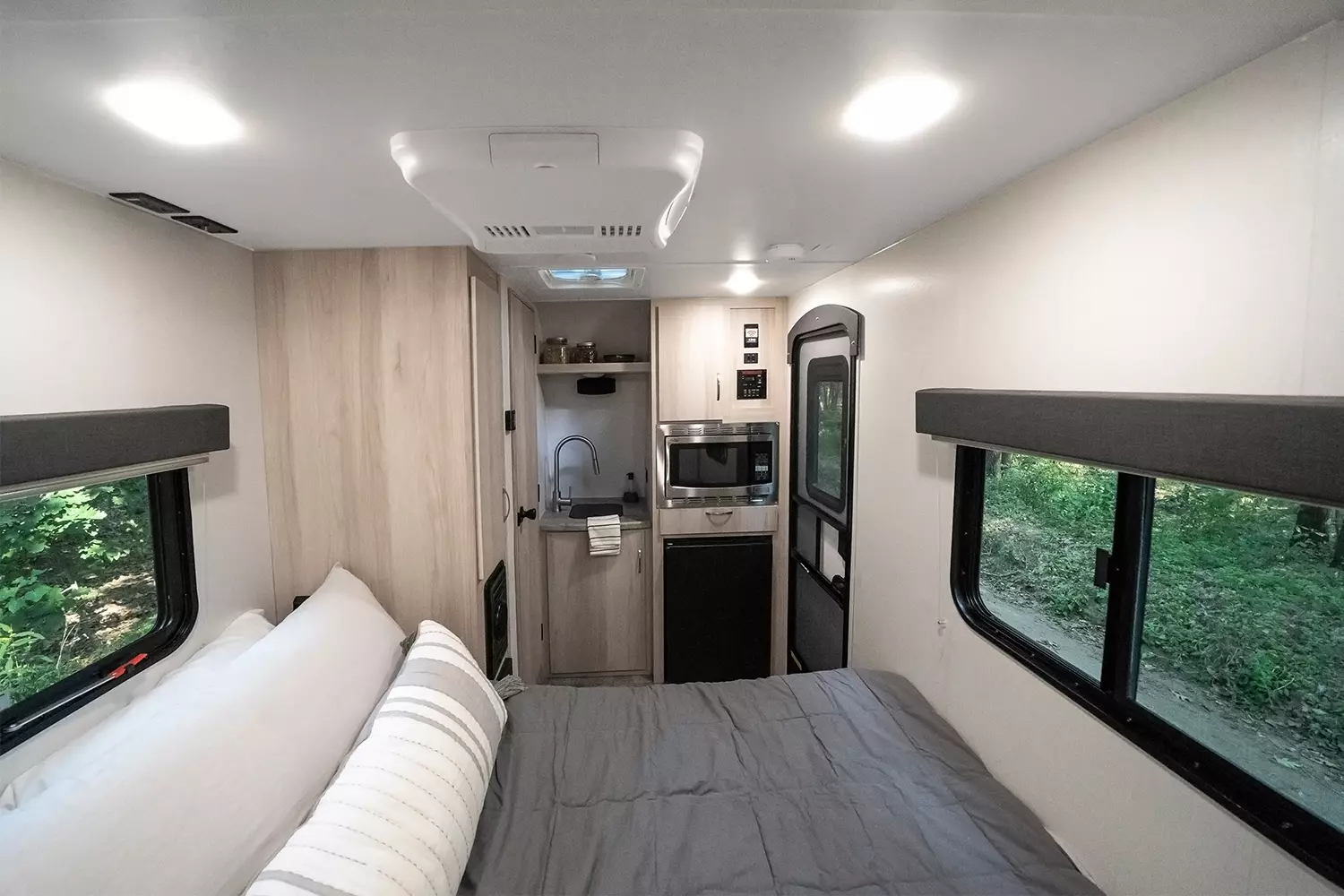 L'intérieur de la nouvelle petite roulotte de voyage Winnebago Hike 100 SUV, comprenant un lit, un évier, un four à micro-ondes, un réfrigérateur et un bain humide