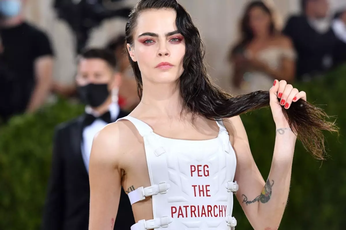 Cara Delevingne draacht in wyt vest mei de wurden