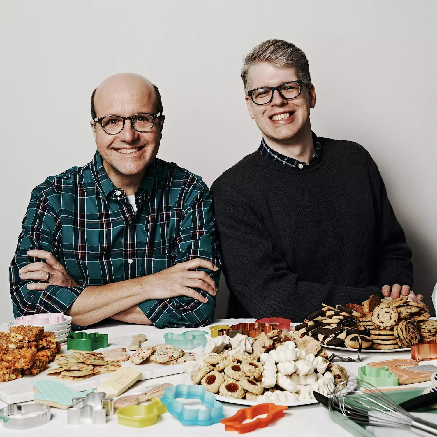 Los expertos en pasteles y panaderos Paul Arguin (izquierda) y Chris Taylor, sentados detrás de una mesa llena de galletas ingeniosamente decoradas