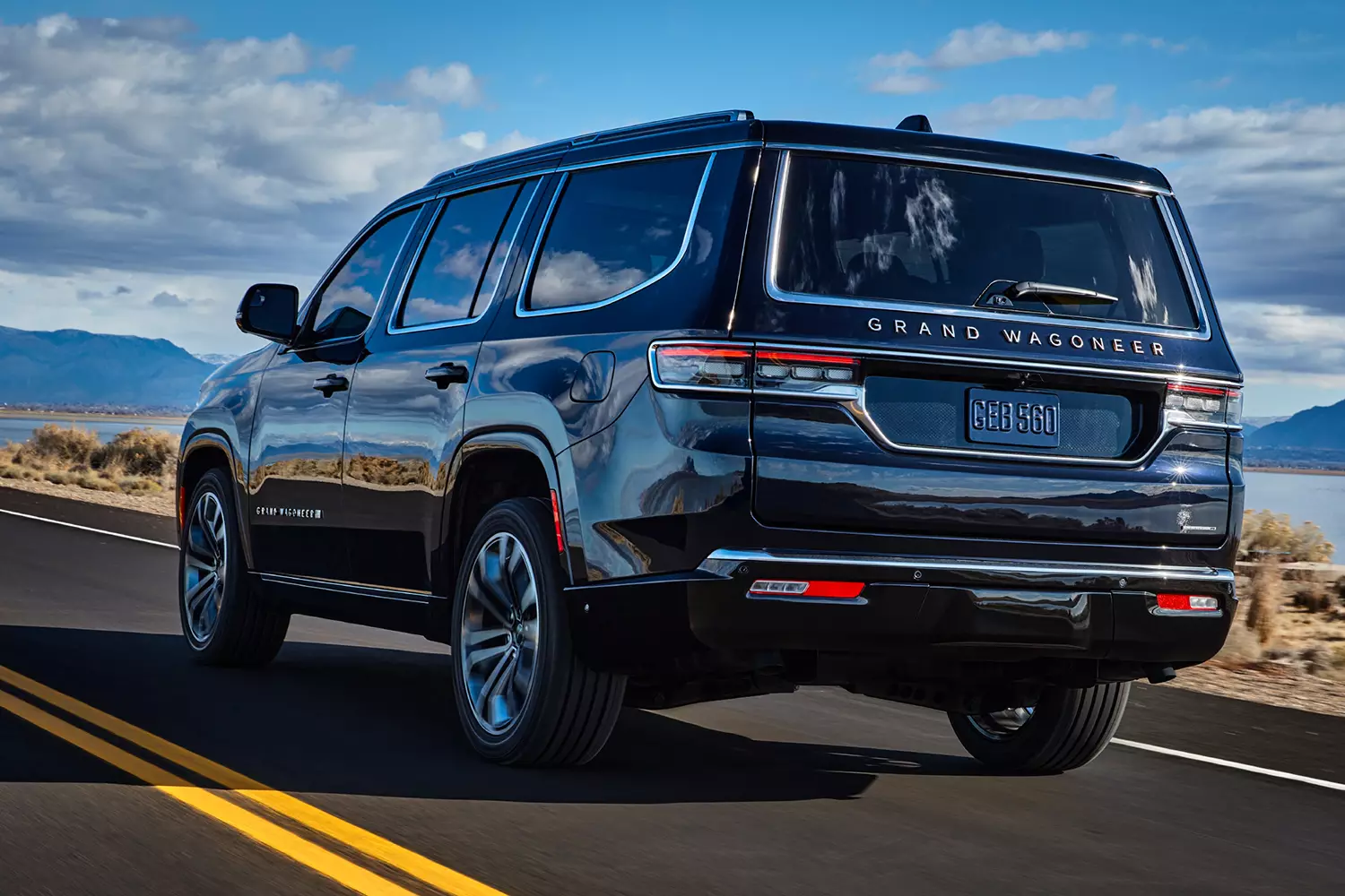 An Jeep Grand Wagoneer 2022 ag tiomáint síos an bóthar lámhaigh ón taobh clé