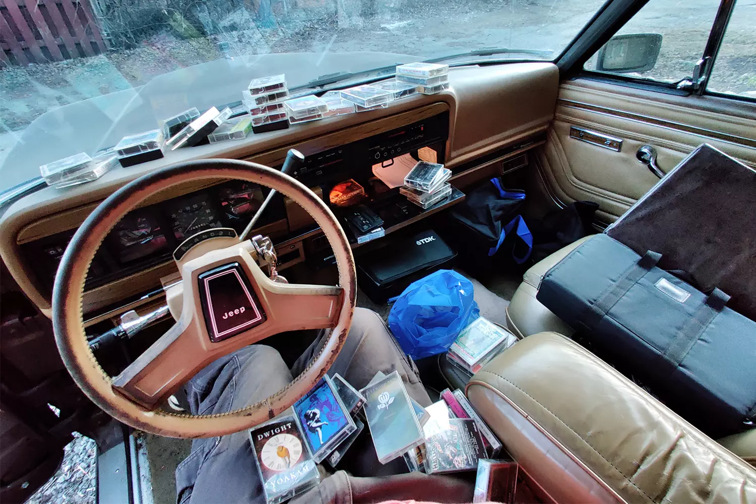 Kursi ngarep loro Jeep Grand Wagoneer 1987 kanthi akeh kaset.