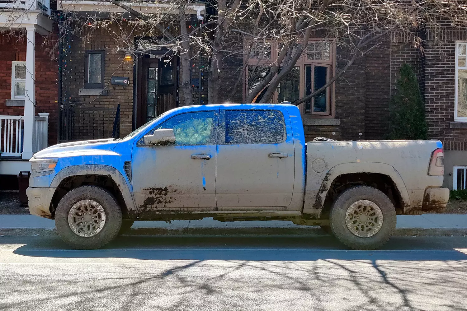 도시 거리에 주차된 진흙으로 뒤덮인 파란색 2021 Ram 1500 TRX 픽업 트럭