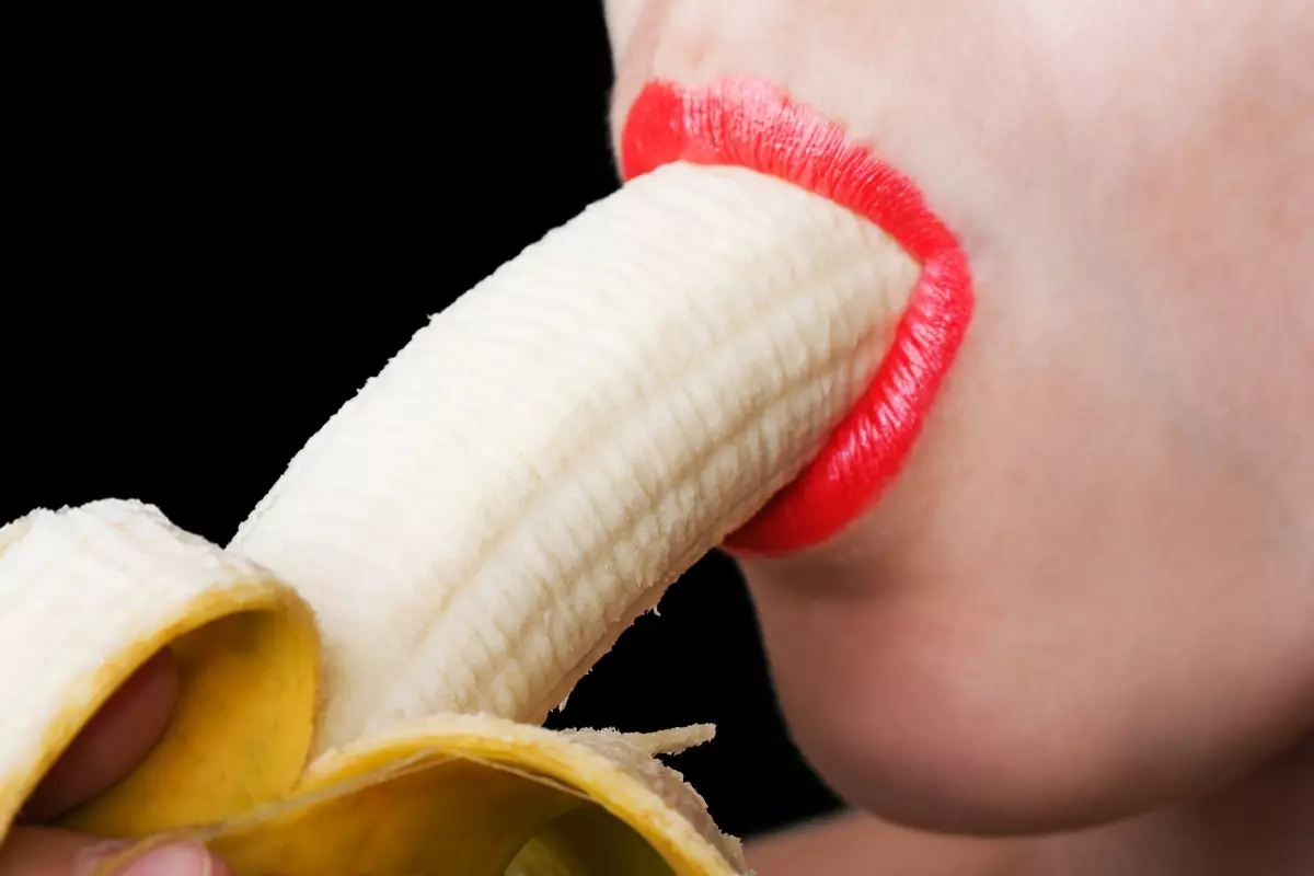 крупный план женщины, сосущей банан