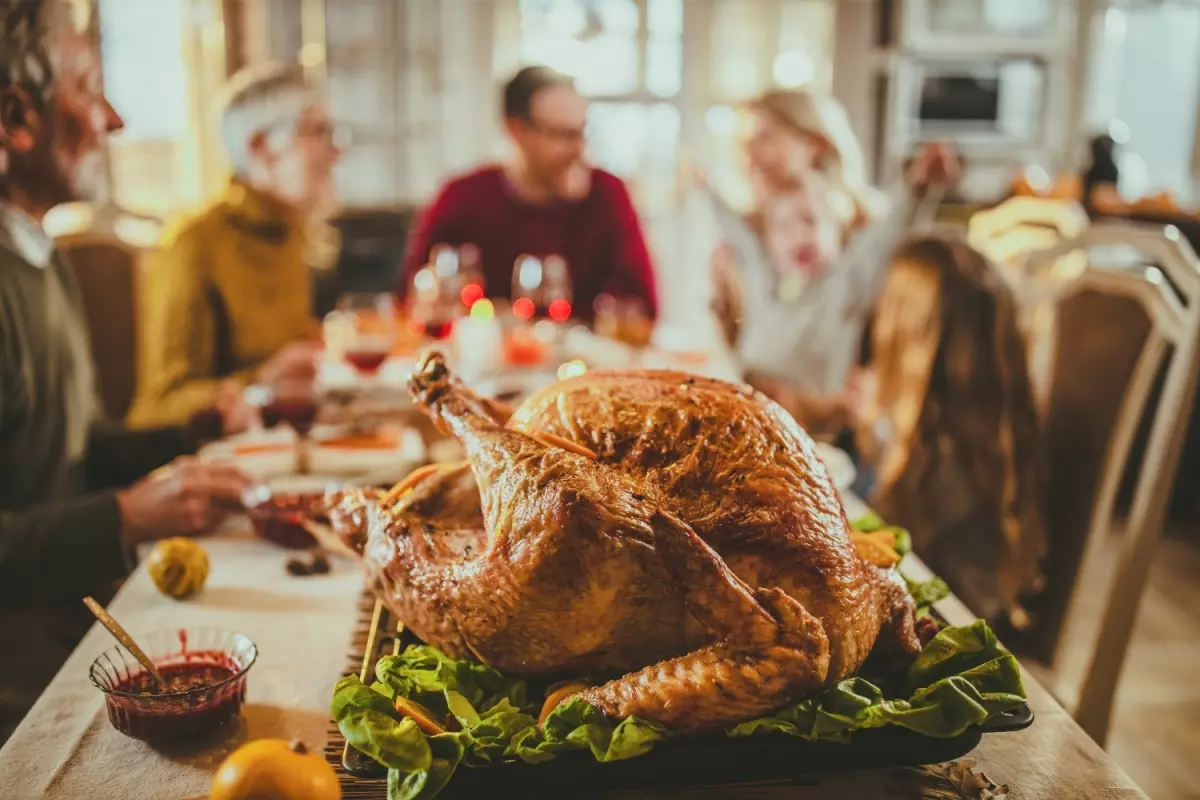 une dinde de thanksgiving affichée sur une table de salle à manger, une famille floue autour d'une table en arrière-plan