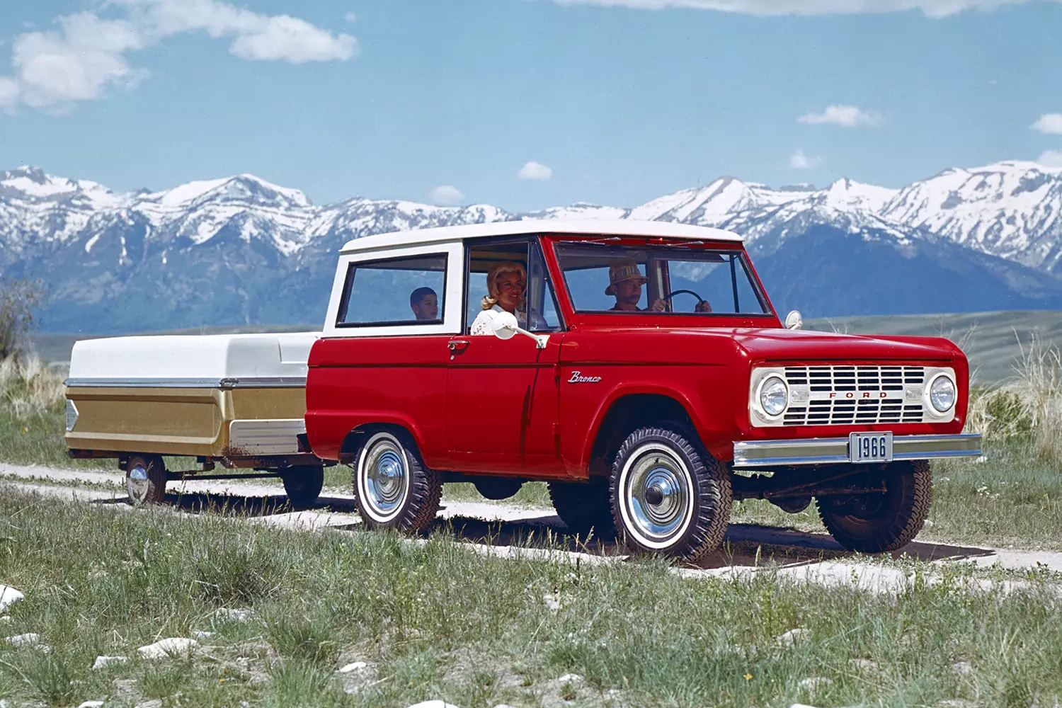 1966 röd och vit Ford Bronco drar en husbil
