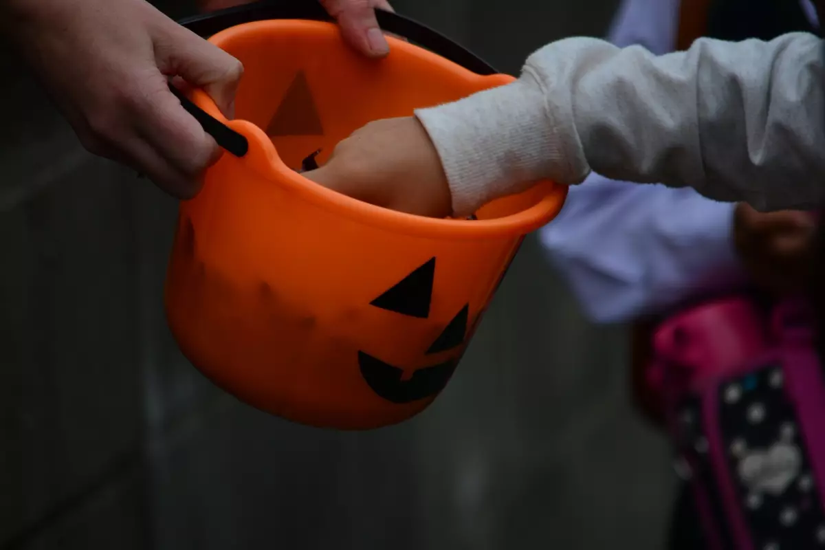 Trick-or-treat timoun yo ak yon bokit joumou zoranj plen sirèt