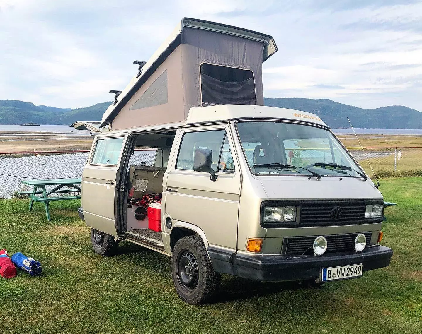 Een foto van een Volkswagen Vanagon Westfalia uit 1990 met de pop-top tent uitgeschoven. Hier is een gids voor het kopen van uw eigen camper.