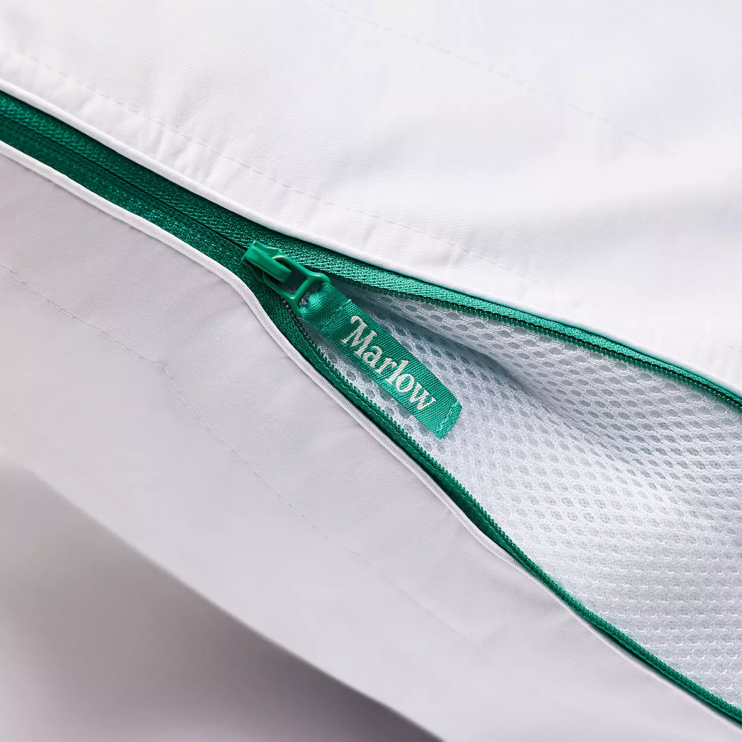 Isang Marlow pillow mula sa bagong sub-brand ng Brooklinen na nagpapakita ng close-up ng berdeng zipper sa gilid na nag-aayos sa katatagan ng unan