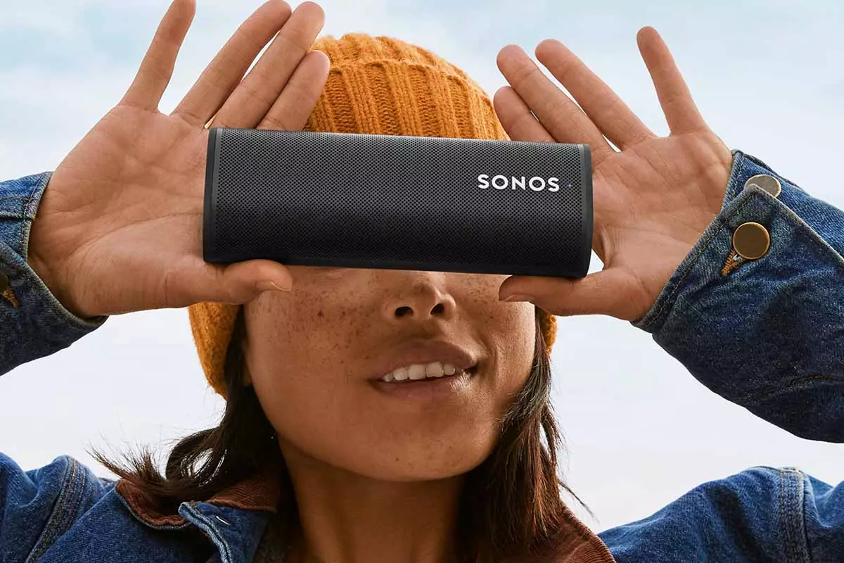 باہر ایک عورت سونوس روم اسپیکر پکڑے ہوئے ہے۔ Sonos نے اپنی اسٹریمنگ سروس پر آؤٹ ڈور ایڈونچر ساؤنڈ اسکیپس فراہم کرنے کے لیے نارتھ فیس کے ساتھ مل کر کام کیا۔