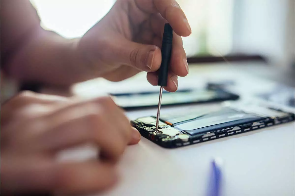 Eng Fra reparéiert en Telefon doheem. Apple huet just en neie Programm ugekënnegt deen d'Clienten erlaabt hir eegen Telefonen ze fixéieren.