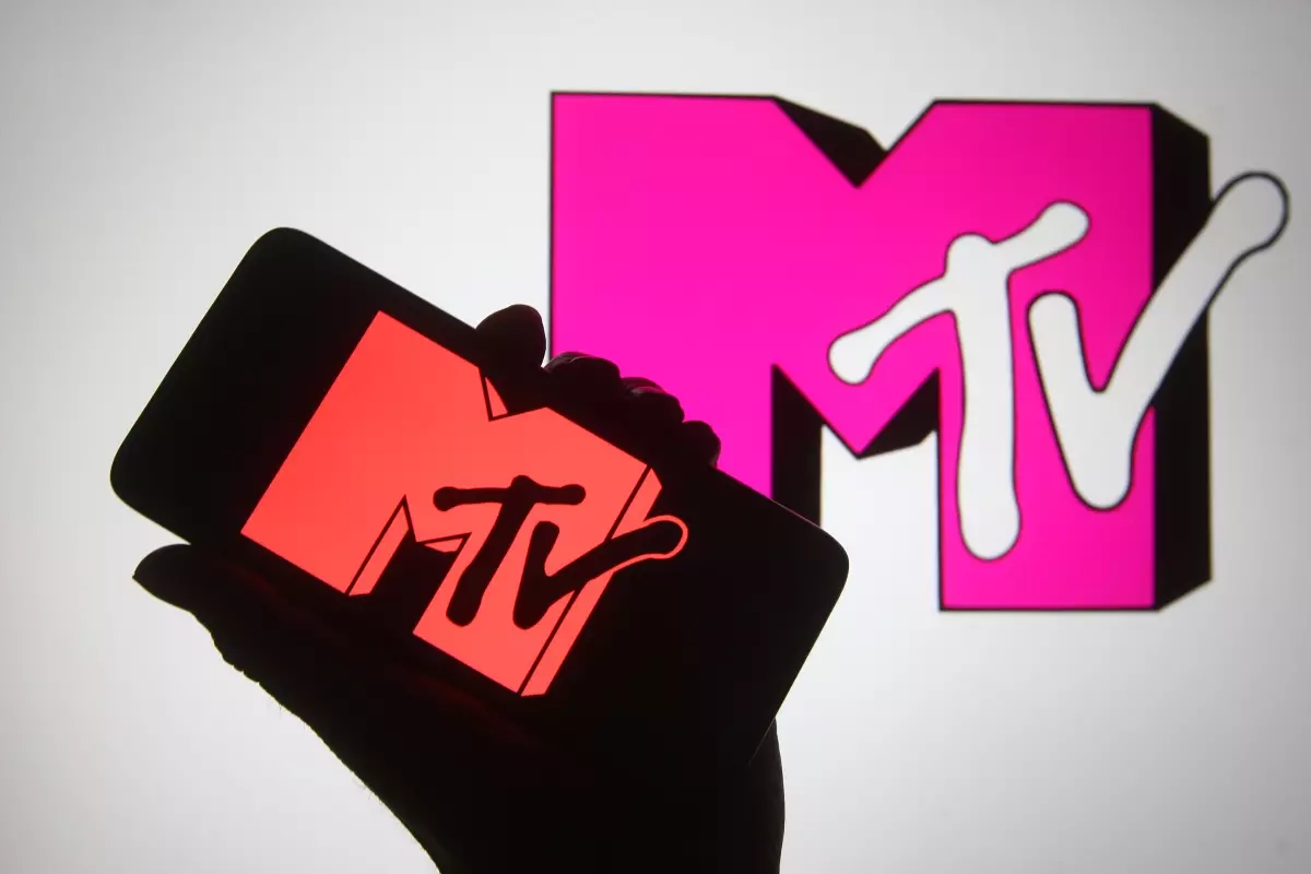 Une main tenant un smartphone avec le logo MTV et le logo MTV derrière en rose